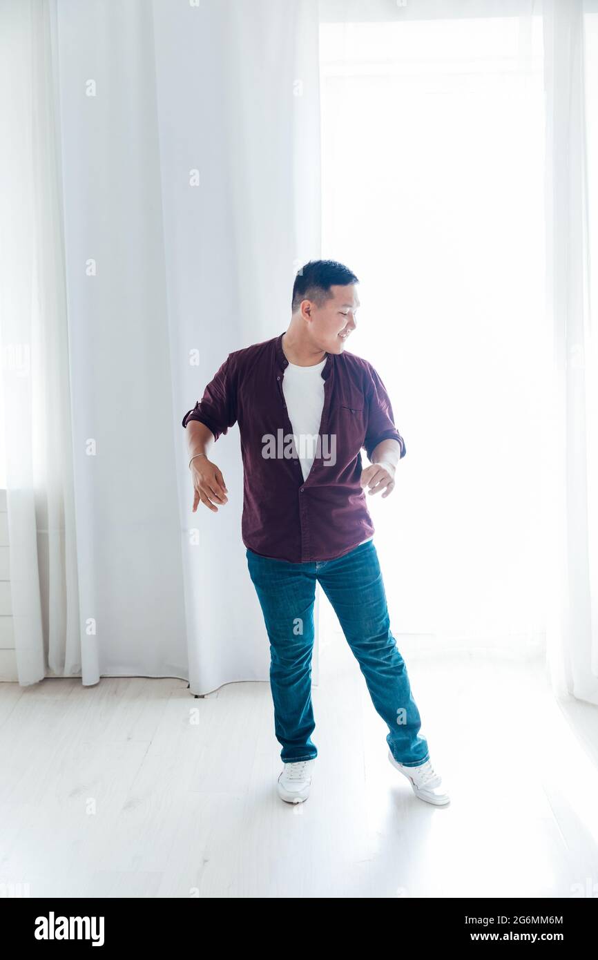 Beautiful Asian man dances to music in white room Stock Photo - Alamy