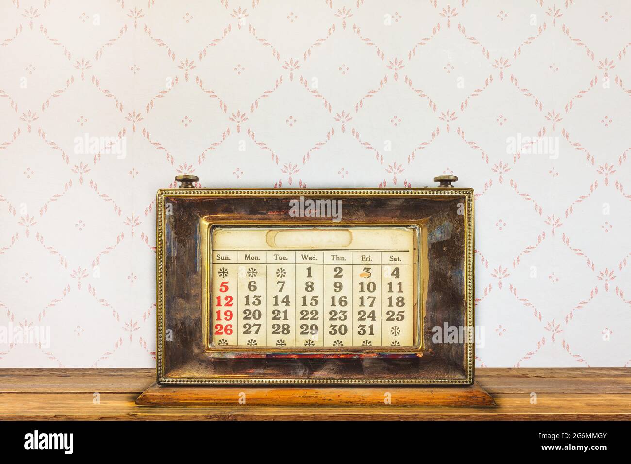 Vintage desktop calendar on a wooden table in front of retro wallpaper ...
