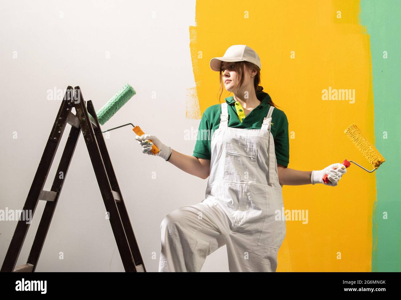 Young women painter in shirt painting a wall with paint roller Stock ...