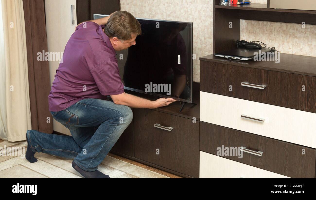 An adult man puts new large TV in place Stock Photo - Alamy