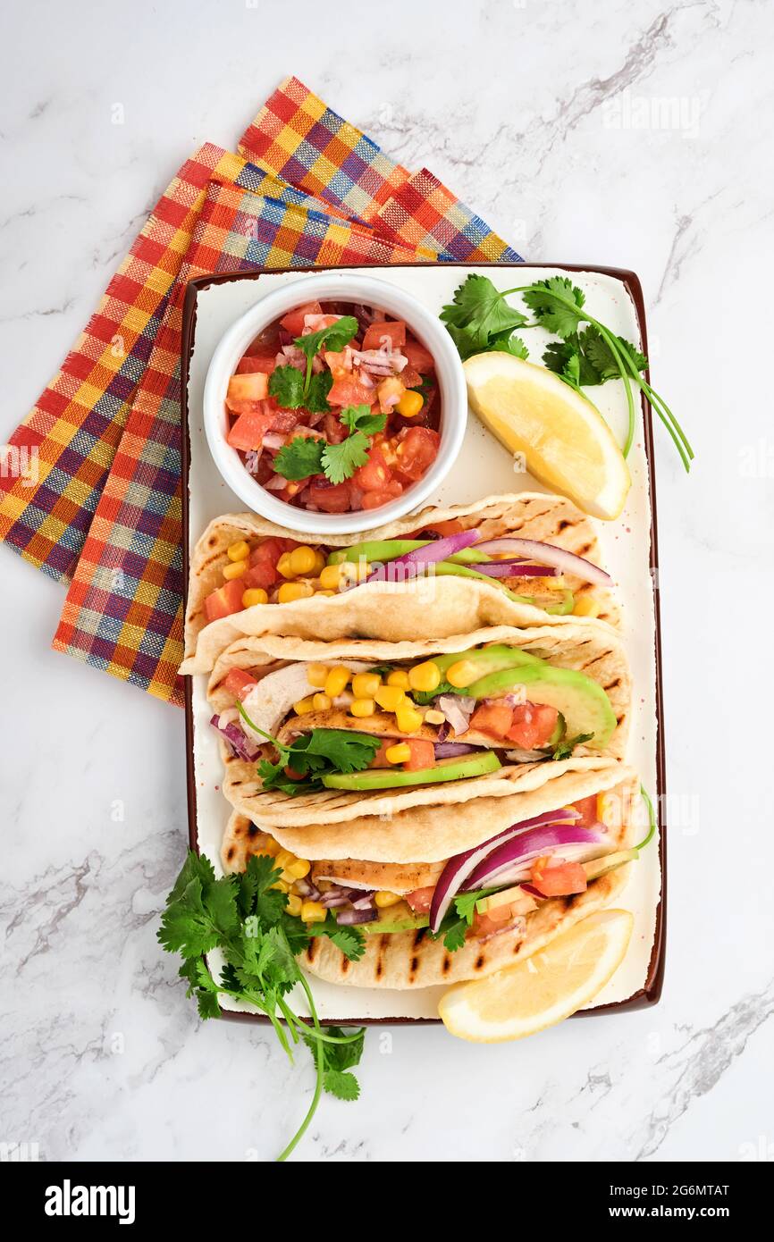 Mexican tacos with grilled chicken, avocado, corn kernels, tomato ...