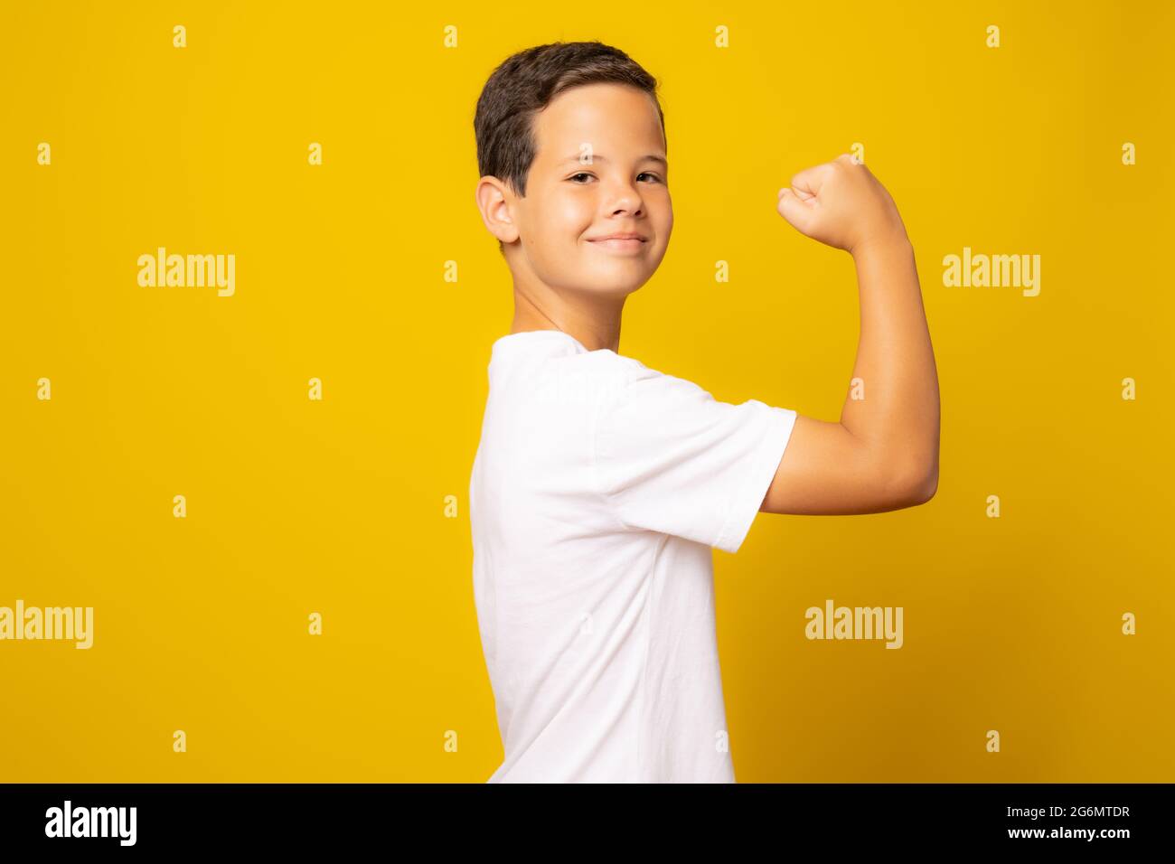 Strong boy showing muscles, isolated on yellow background Stock Photo ...