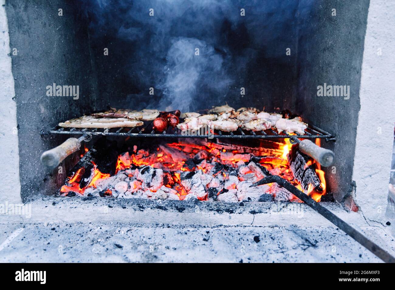 Detail of a barbecue with meat cooking on the embers of the grill ...