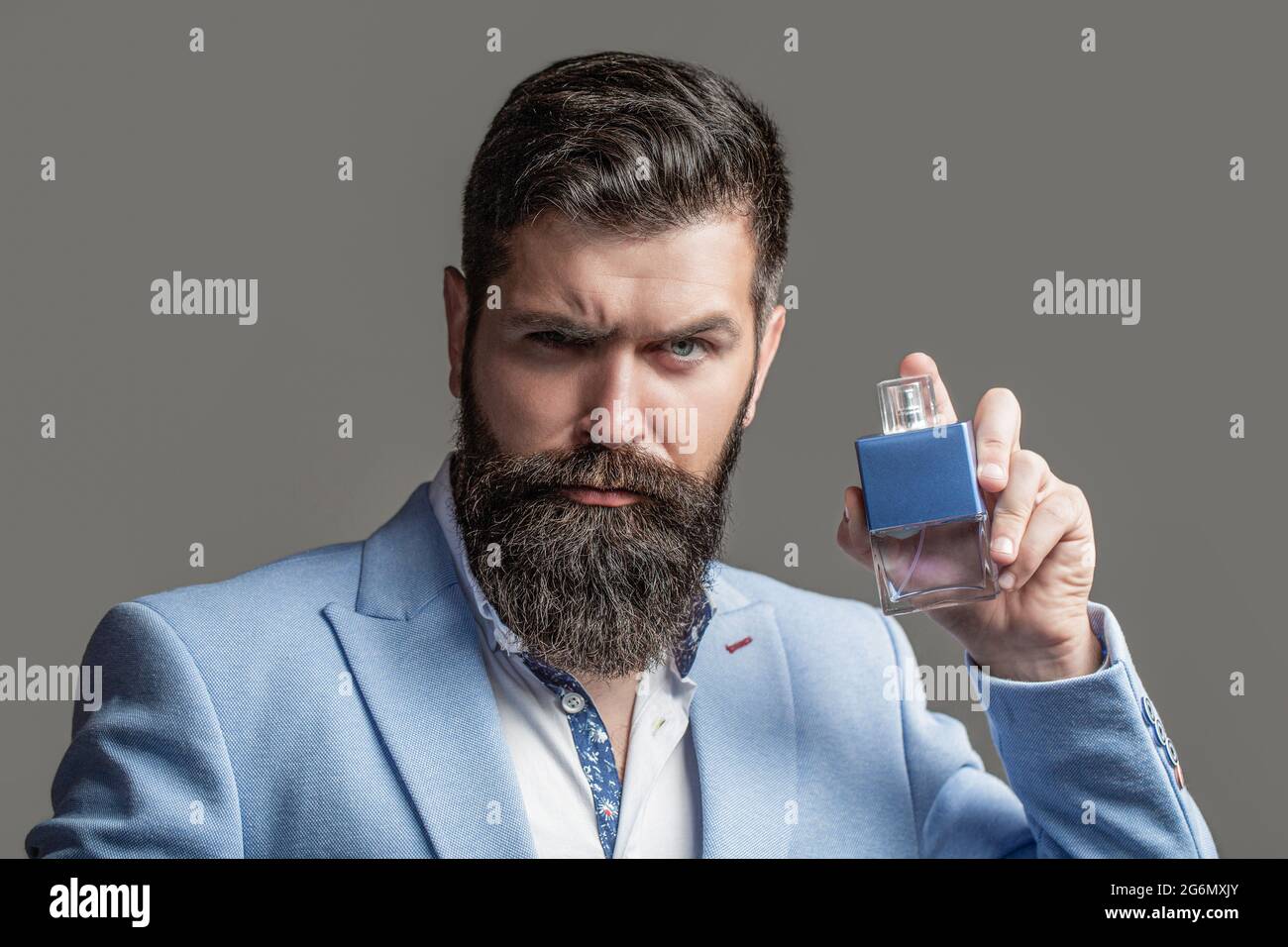 Masculine perfumery, bearded man in a suit. Male holding up bottle of ...