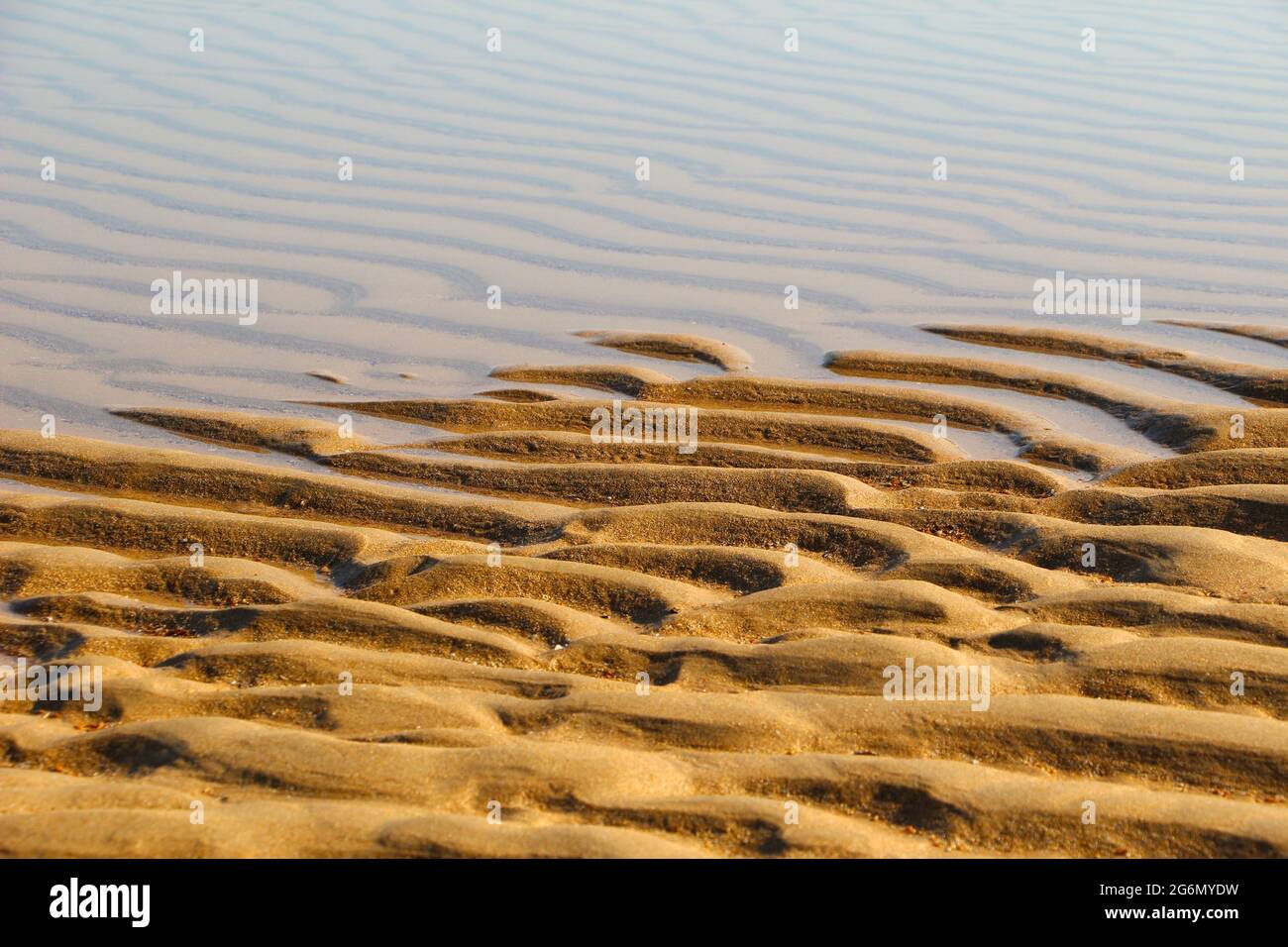 Sand rippled by receding sea water with half submerged Stock Photo - Alamy