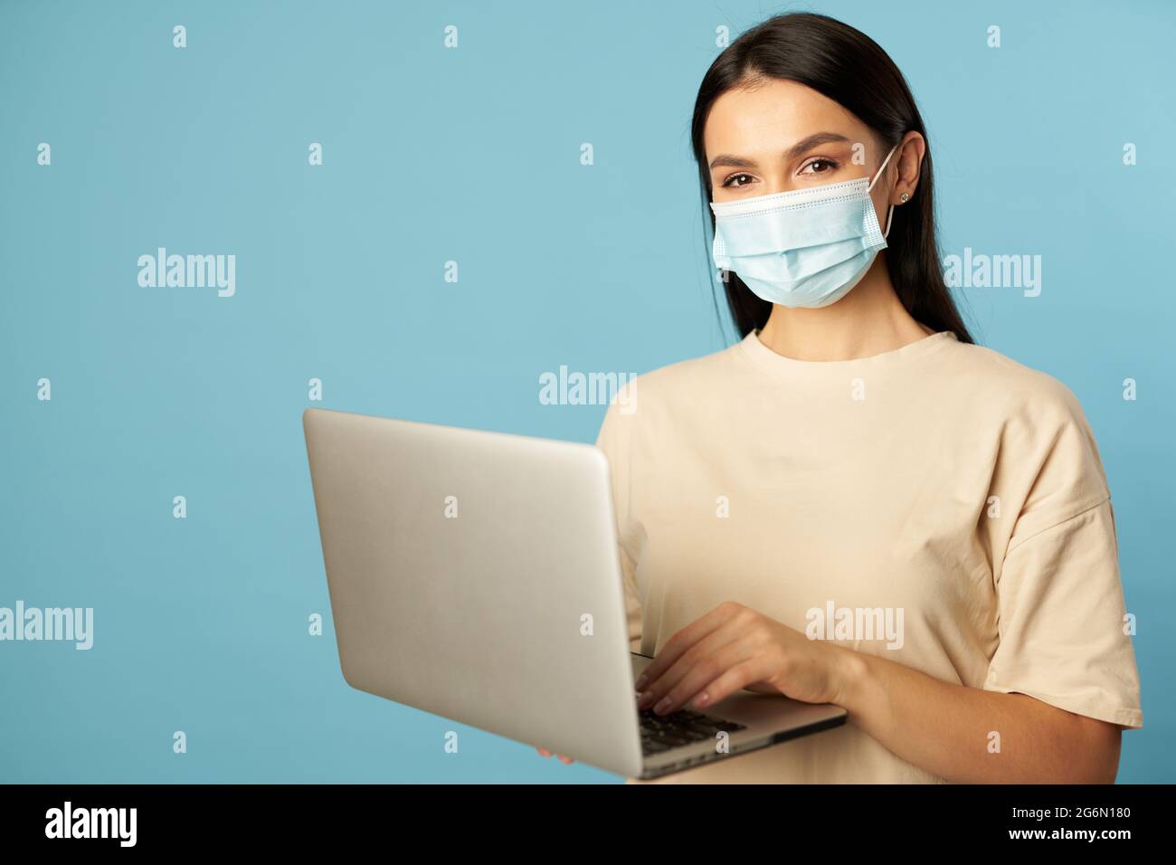 Pretty lady in face mask posing with laptop while typing Stock Photo ...