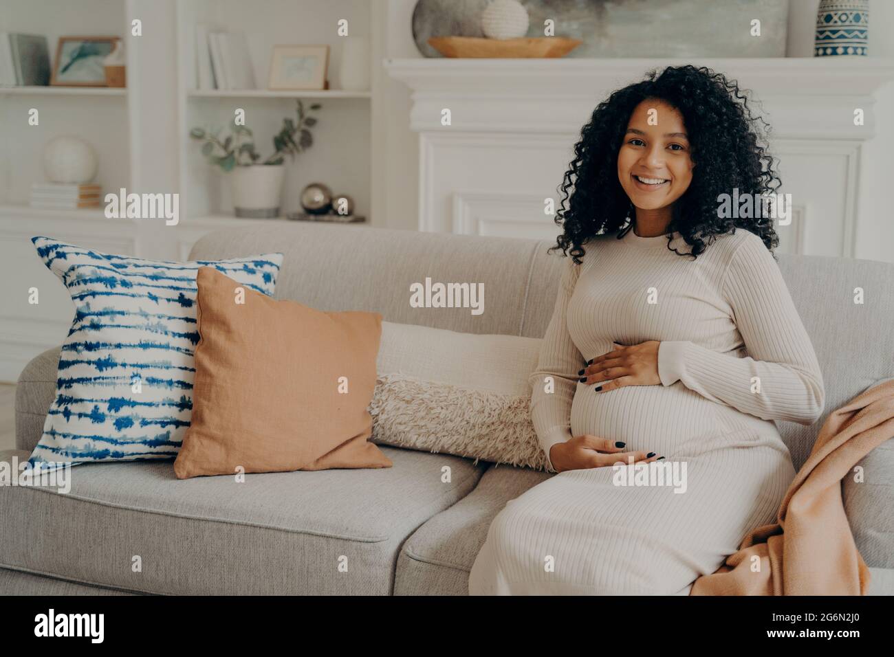 Smiling pretty black expectant young mom feeling relaxed and enjoying ...