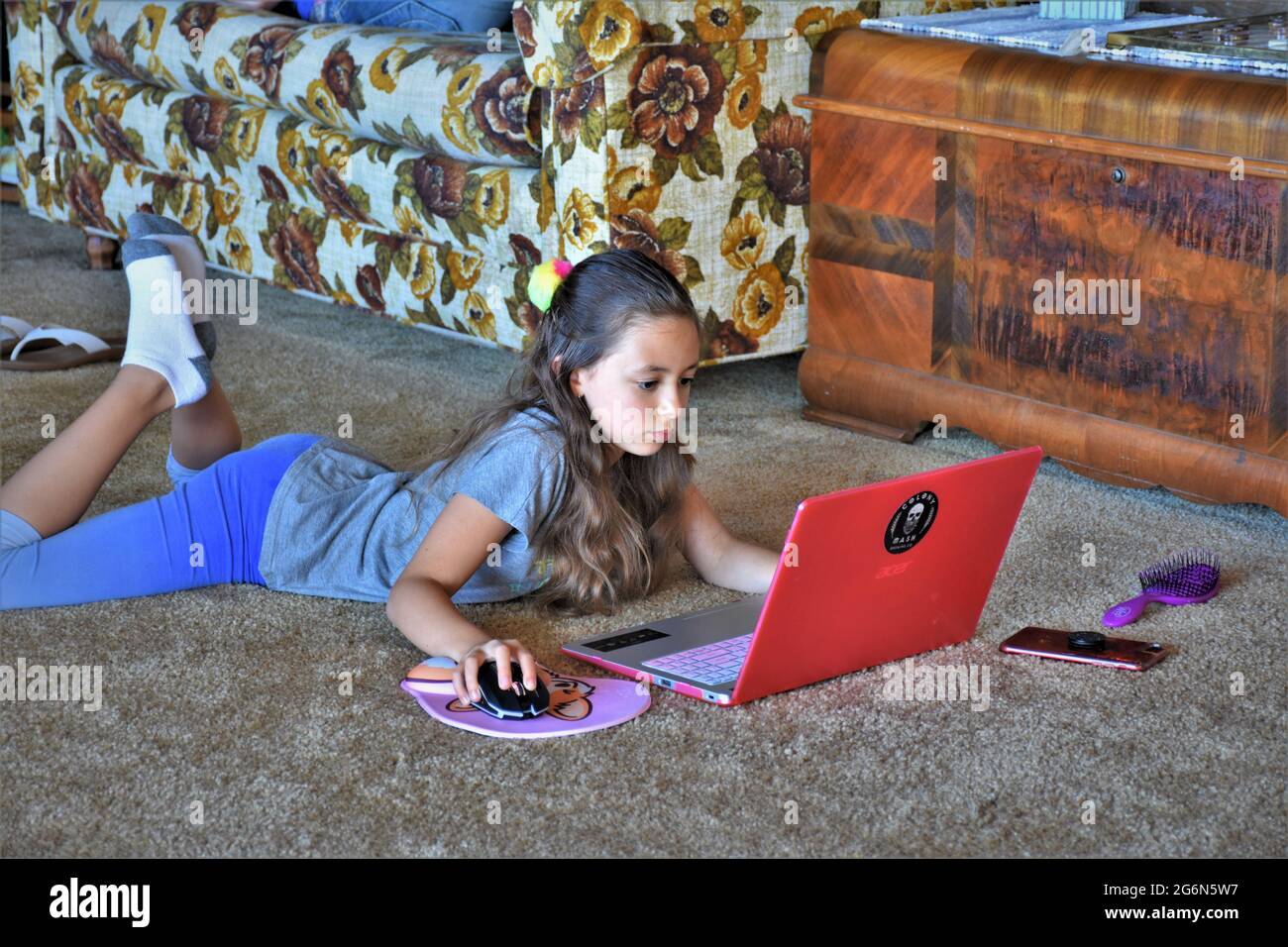 8 year old Caucasian girl working on homework on the floor alone during ...