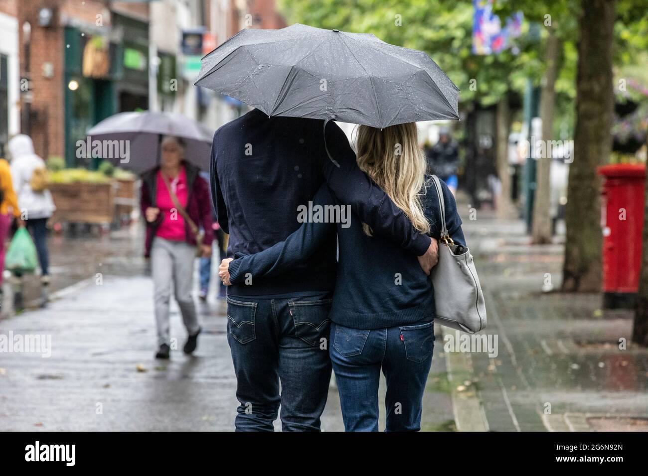 Loving couple walk holding each other on a rainy day along the high ...