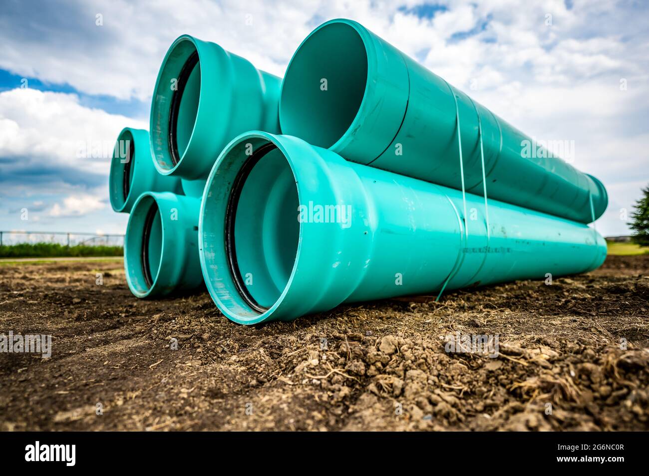 Stacked water main pipe with bell fitting next to an exposed trench for ...