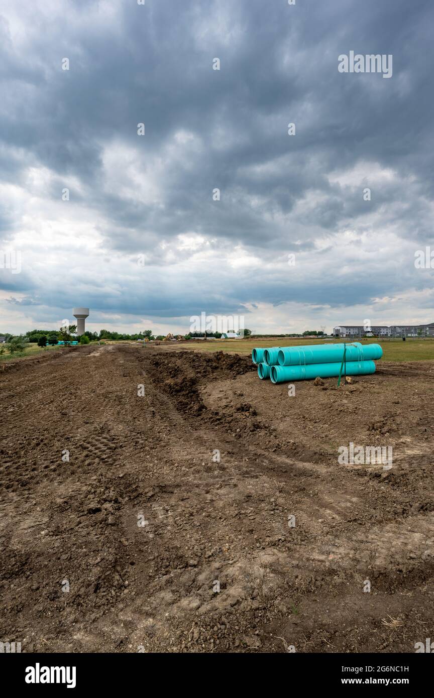Stacked water main pipe with bell fitting next to an exposed trench for ...