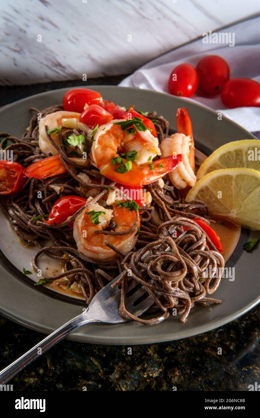 Italian shrimp Gamberoni Aglio e Olio with black pasta and cherry ...