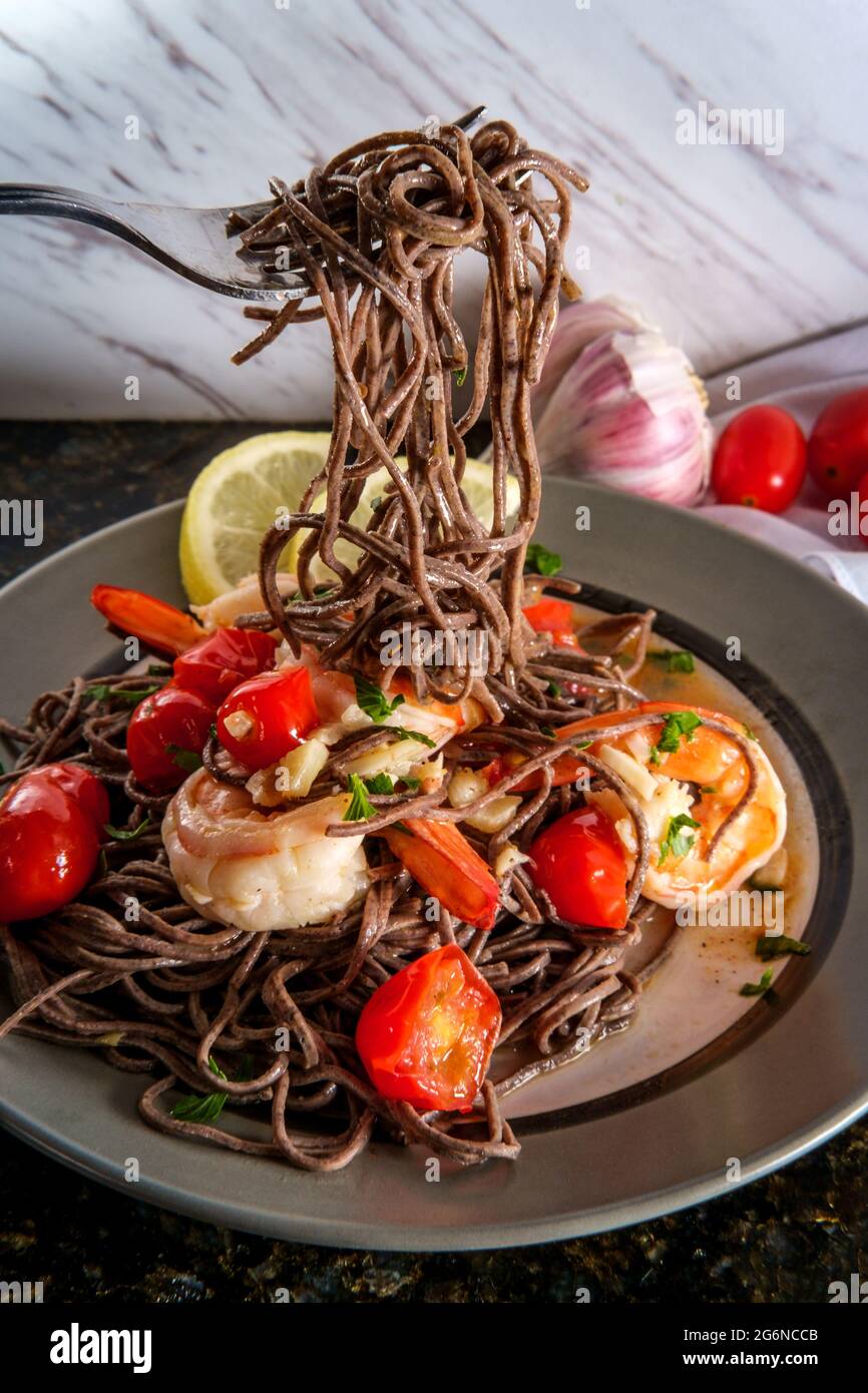Italian shrimp Gamberoni Aglio e Olio with black pasta and cherry ...