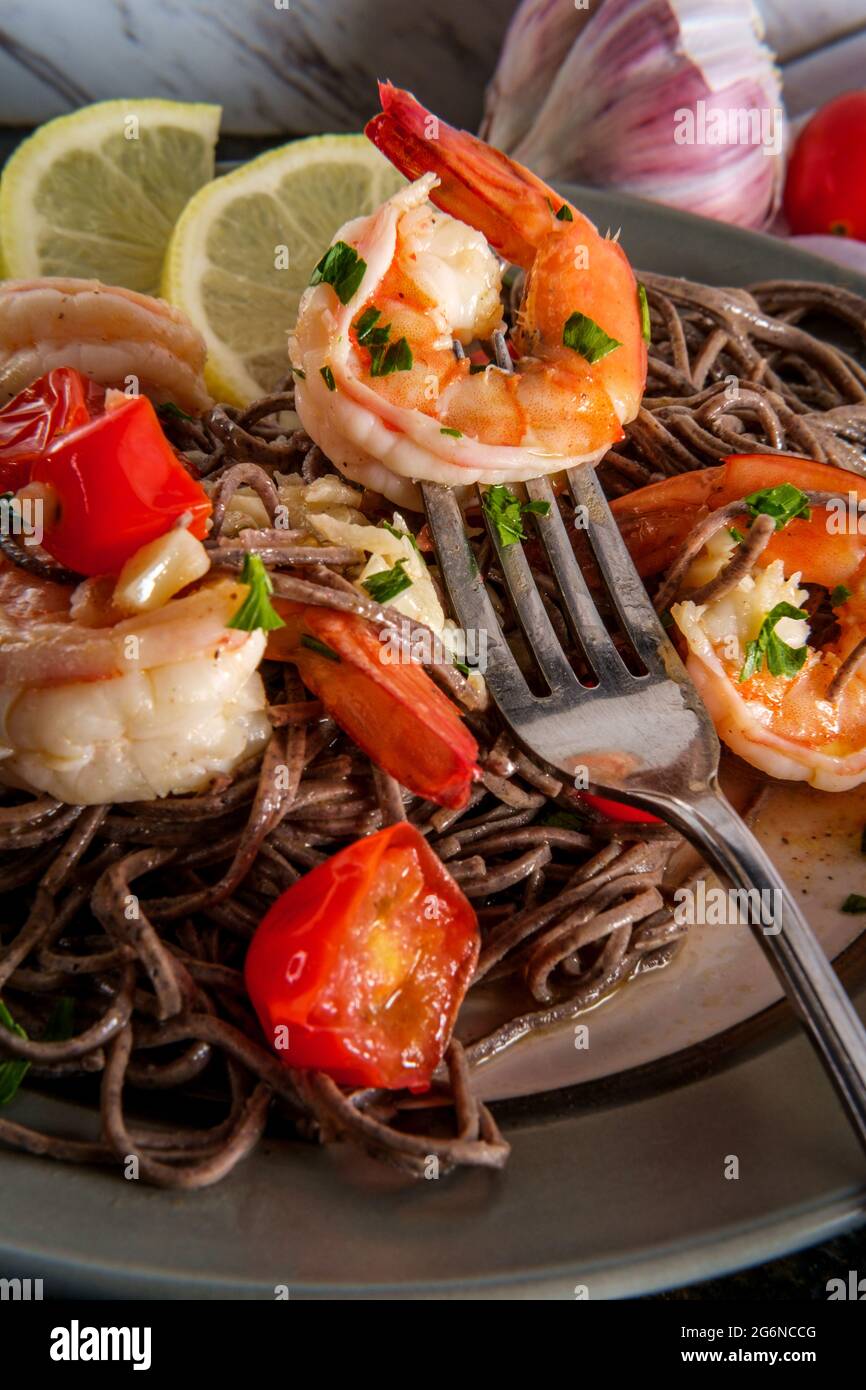 Italian shrimp Gamberoni Aglio e Olio with black pasta and cherry ...