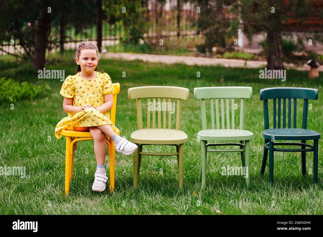 a cute, mischievous child is sitting on chairs and waiting for friends ...