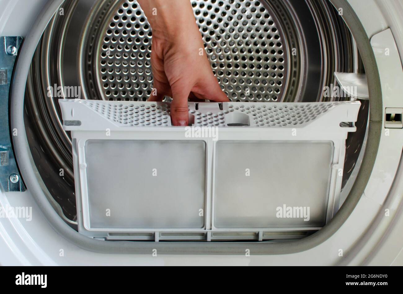 A housewife holds a lint trap from a front-loading dryer. A woman's ...