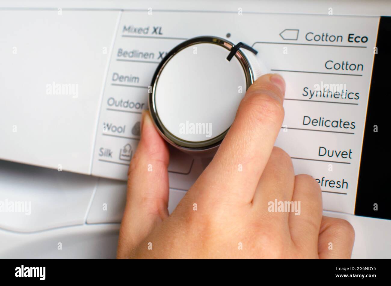 Hand turning the knob of the tumble dryer to adjust the temperature ...