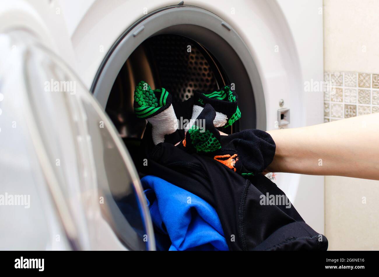 Woman loads the washing machine, washing sportswear. Washing Colorful ...
