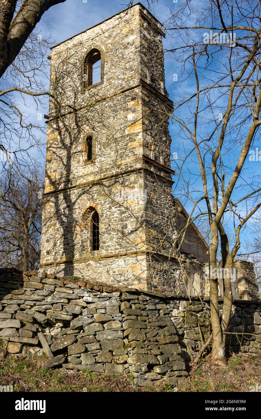 A half-demolished stone church behind the enclosure wall with blue sky ...