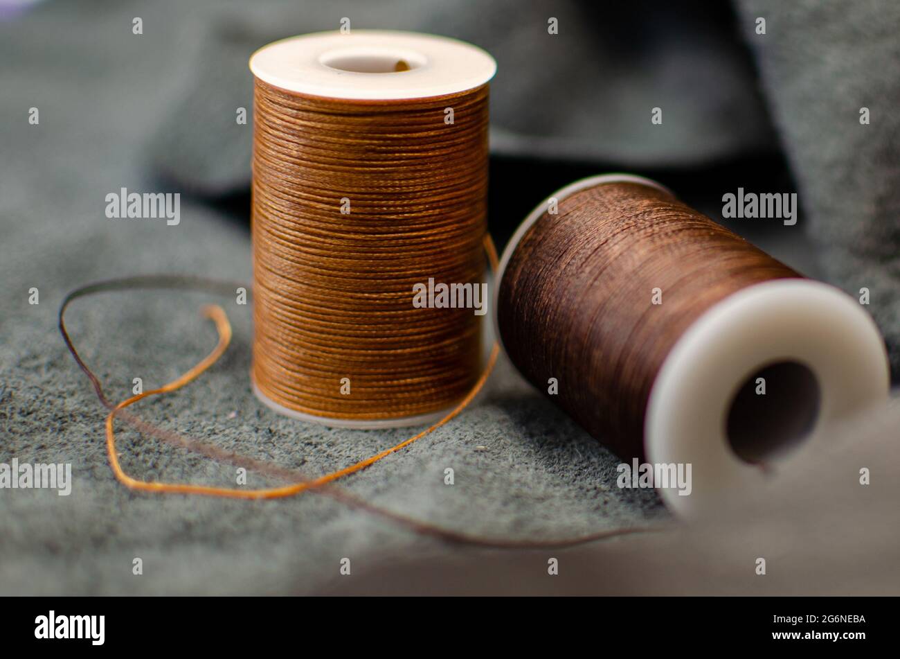 two spools of brown thread on a black inverted leather background Stock ...