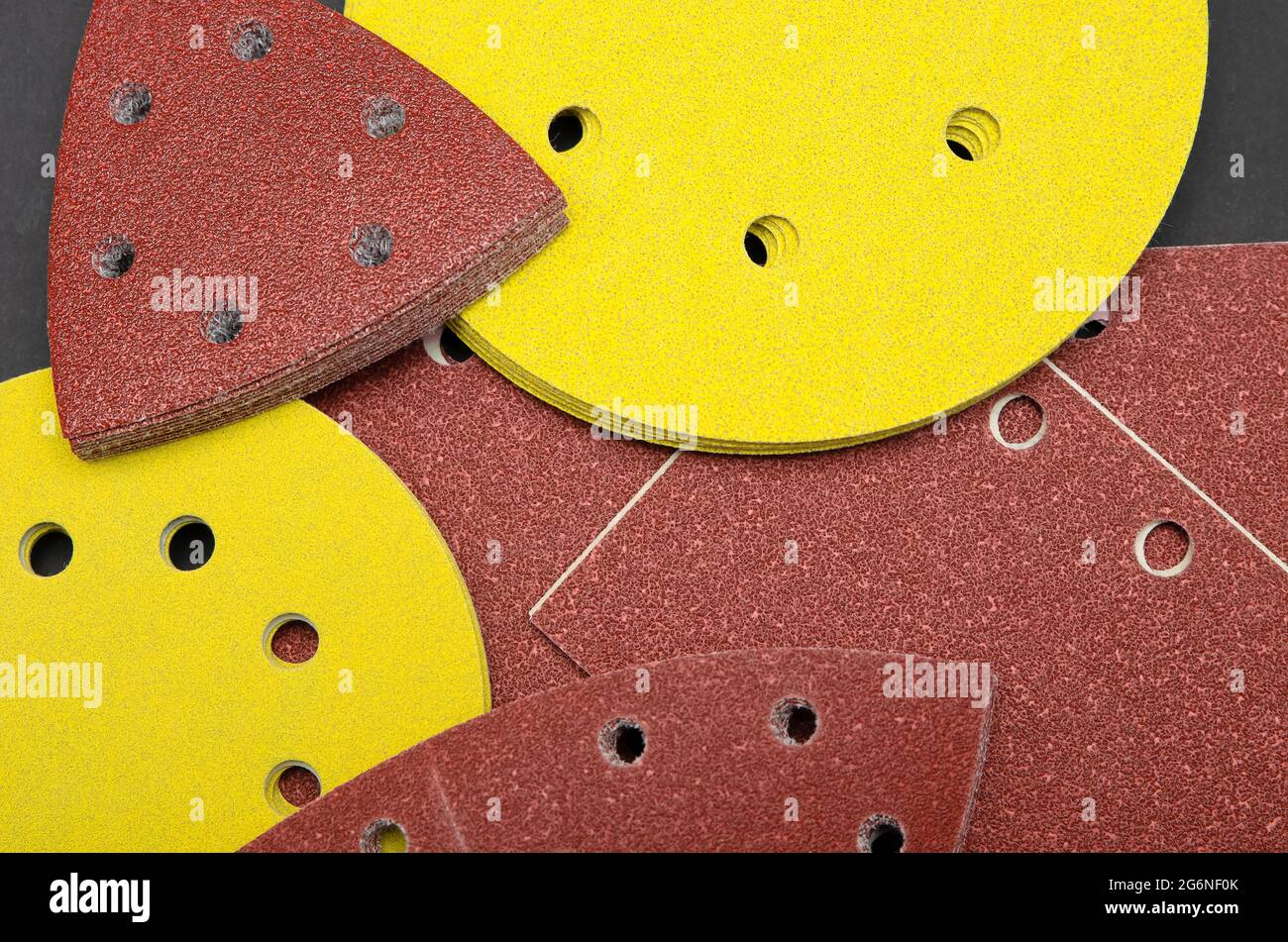 Sandpaper for sanding wood, on a black background. A stack of yellow ...