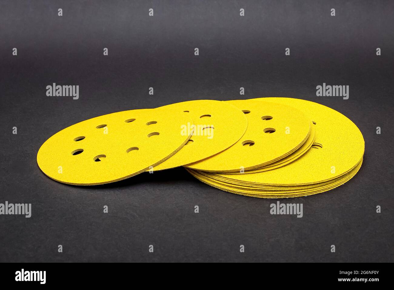 Sandpaper for sanding wood, on a black background. A stack of yellow ...