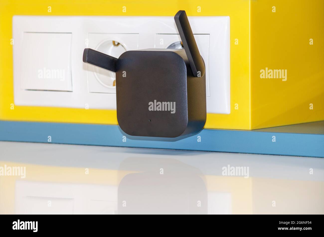 WiFi repeater in an electrical outlet on a yellow wall. An easy way to ...