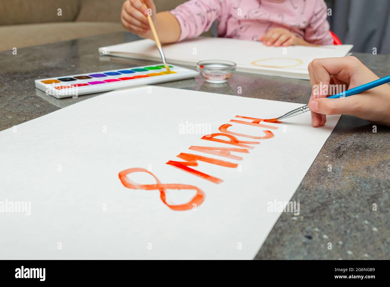 womens day, children draw with paints, on a white sheet of paper ...