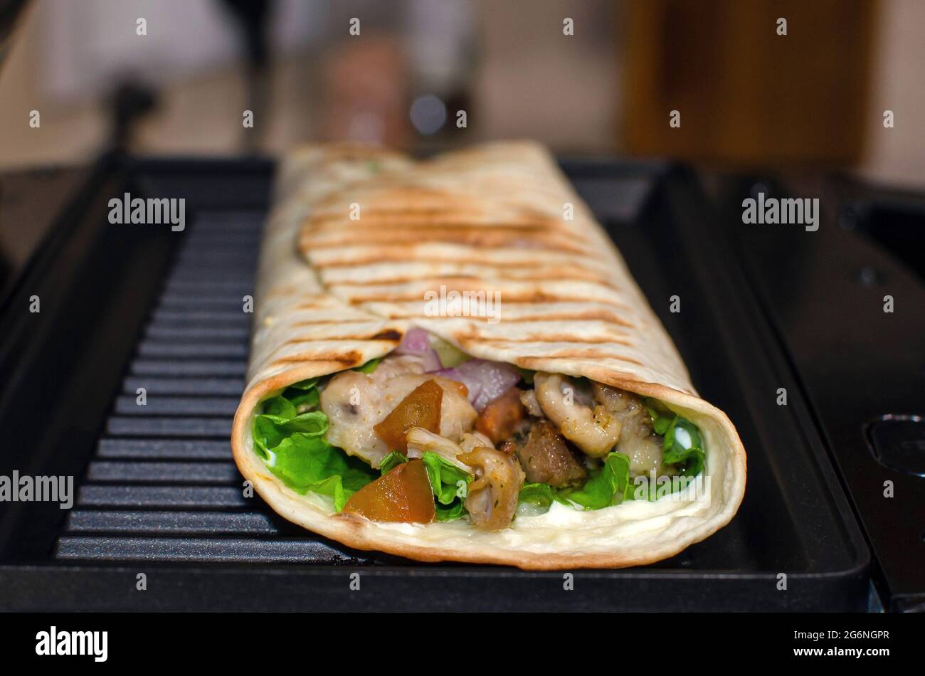 Roll of pita bread, vegetables and chicken. Cooking on an electric ...