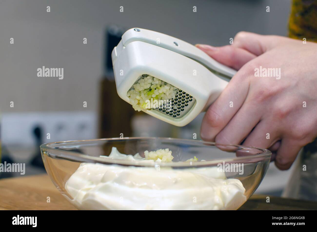 Garlic press made of stainless steel and white plastic. Making garlic ...