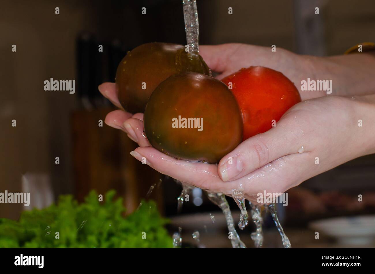 Washing tomatoes under the tap. The focus is shallow and where the ...