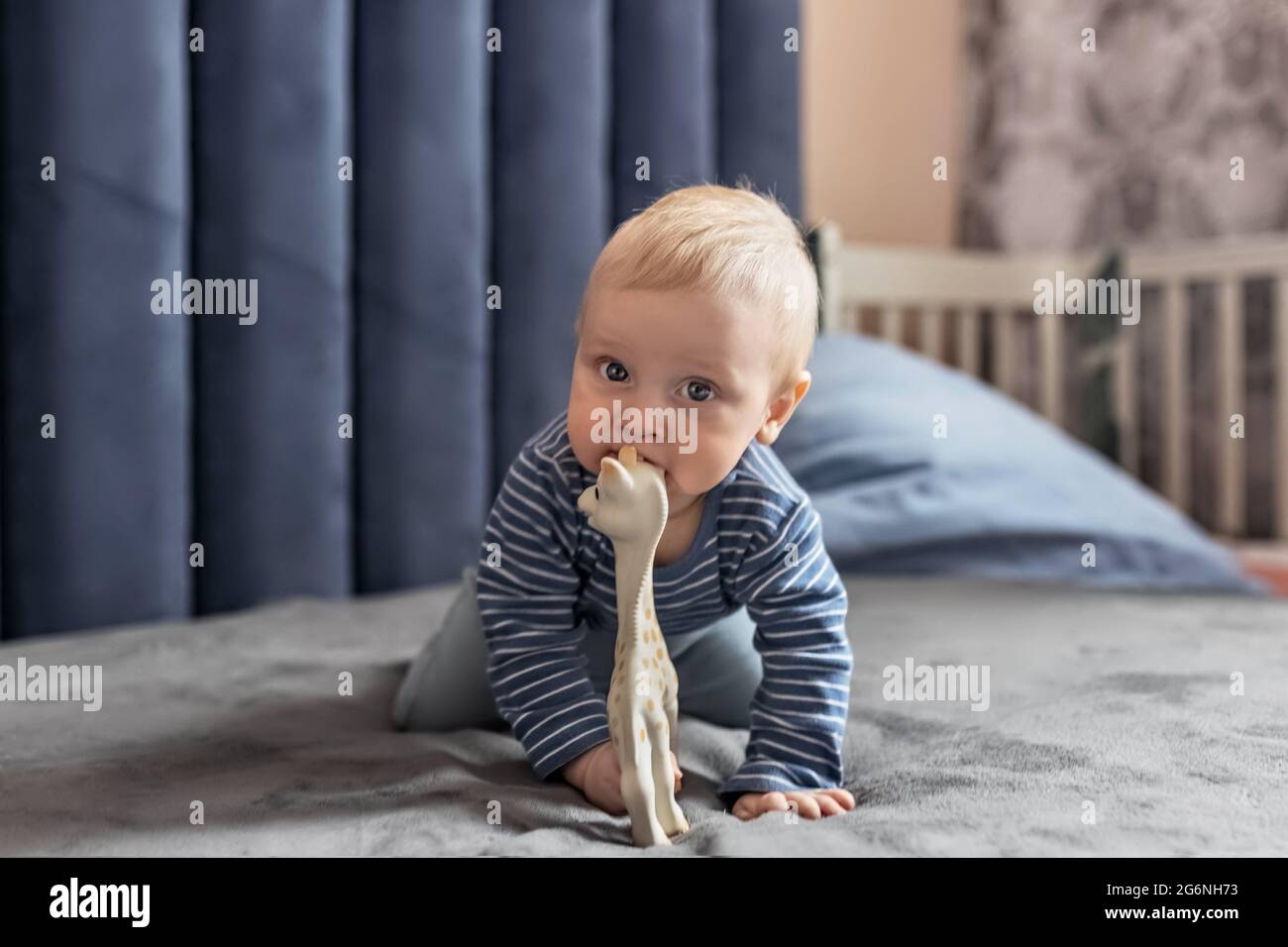 A small infant with a toy on the bed. Childhood Stock Photo - Alamy