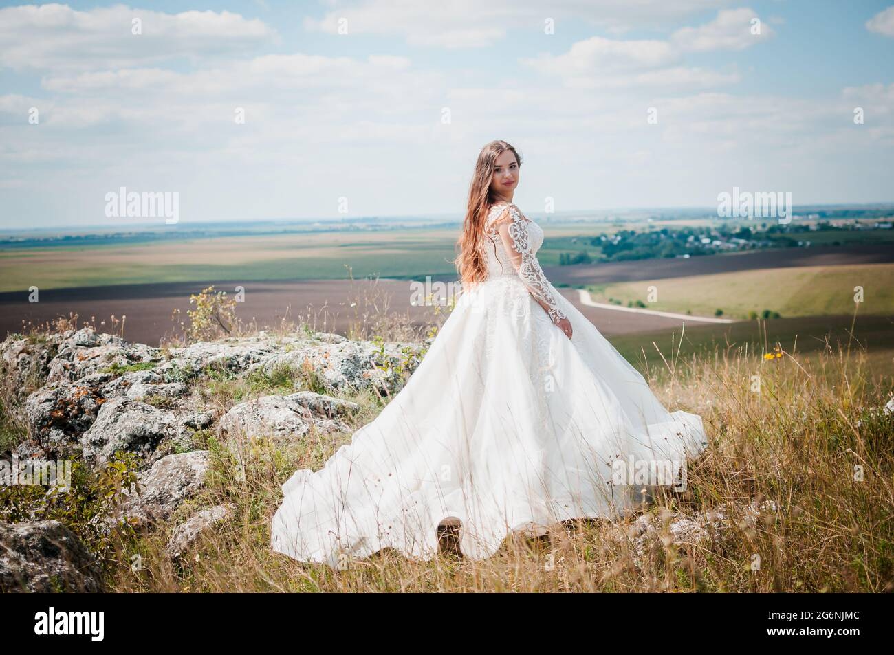 A girl in a white wedding dress stands against the backdrop of a ...