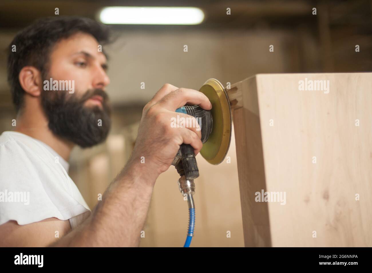 Craftsman is using an electric sander, to smoothen the wood texture ...