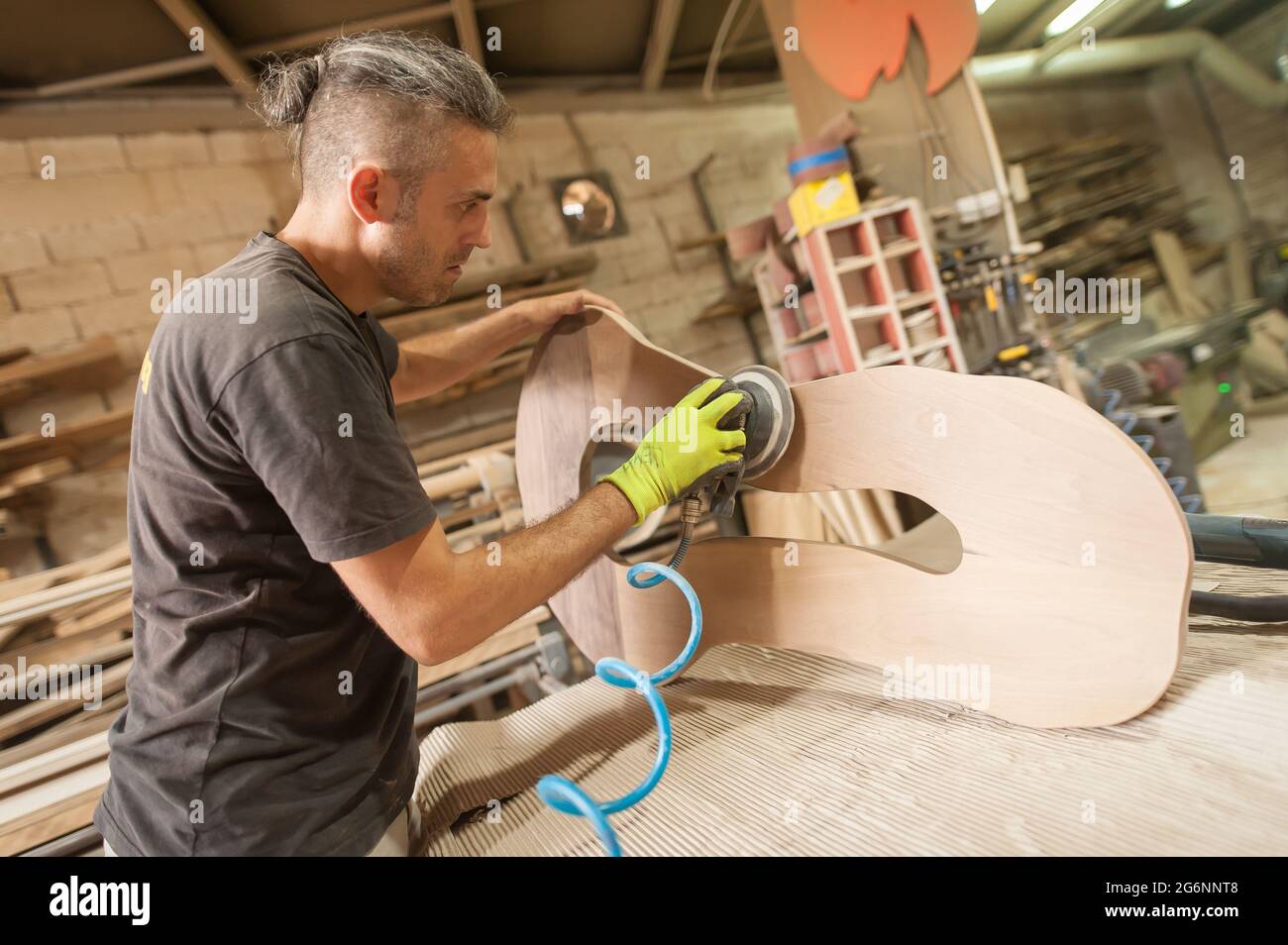 Craftsman is using an electric sander, to smoothen the wood texture ...