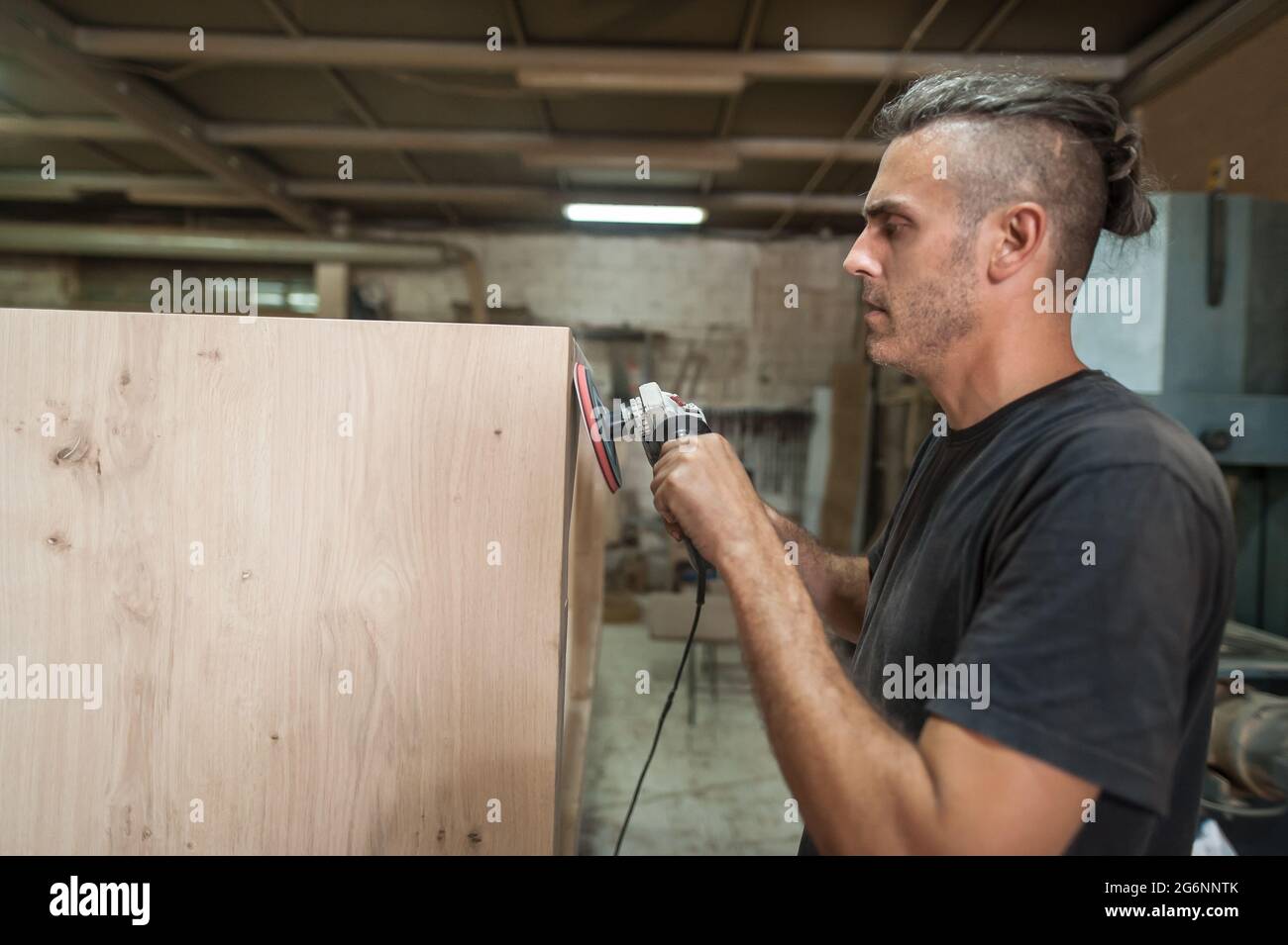 Craftsman is using an electric sander, to smoothen the wood texture ...