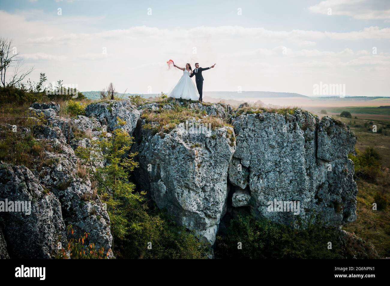 Newlyweds on the background of rocks and hold colorful smoke in their ...