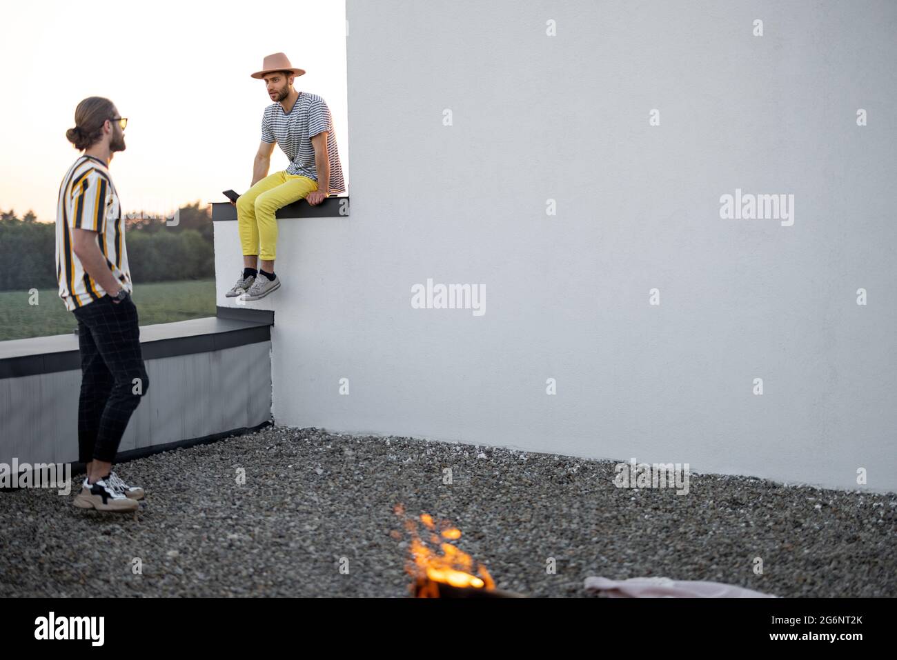 Two male friends talk at rooftop on sunset Stock Photo - Alamy