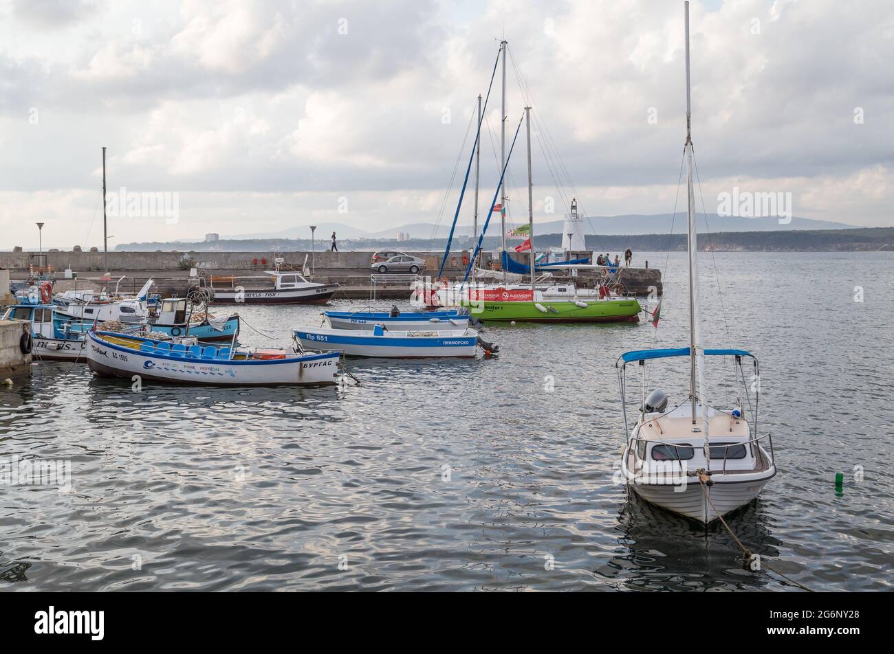 Port - small lighthouse, fishermen, yachts and fishing boats against ...