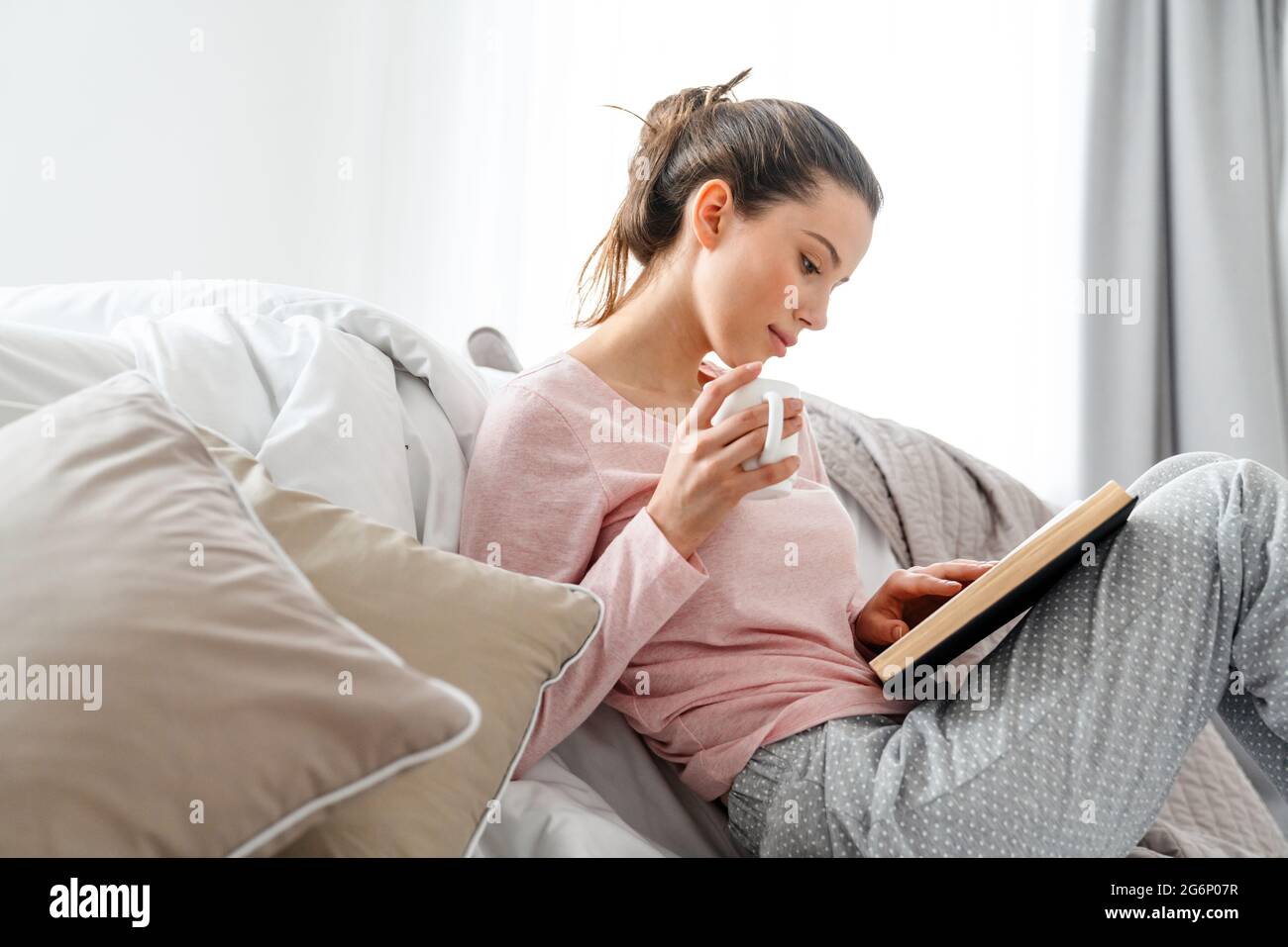 Young smiling white woman reading book studying sitting on a floor of ...