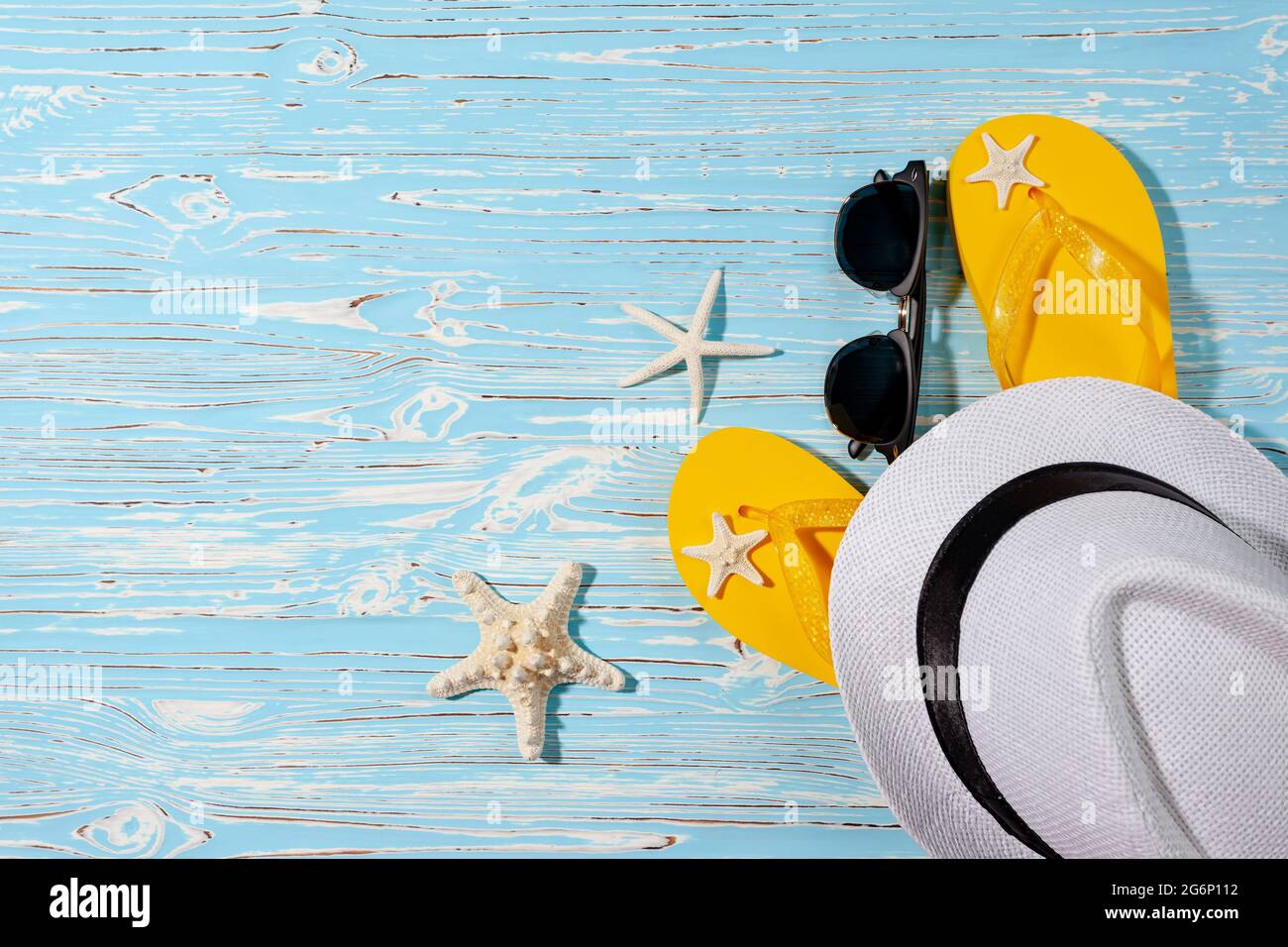 yellow rubber flip flops, white beach hat, starfish on a blue wooden ...