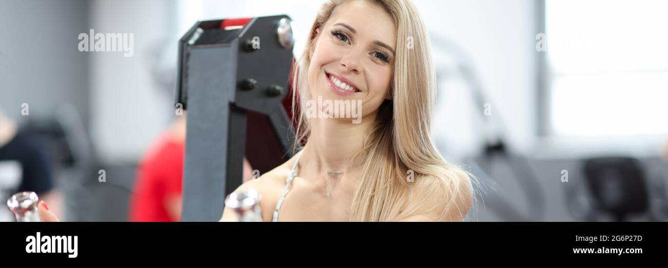 Sportive woman doing exercises for biceps on simulator Stock Photo - Alamy