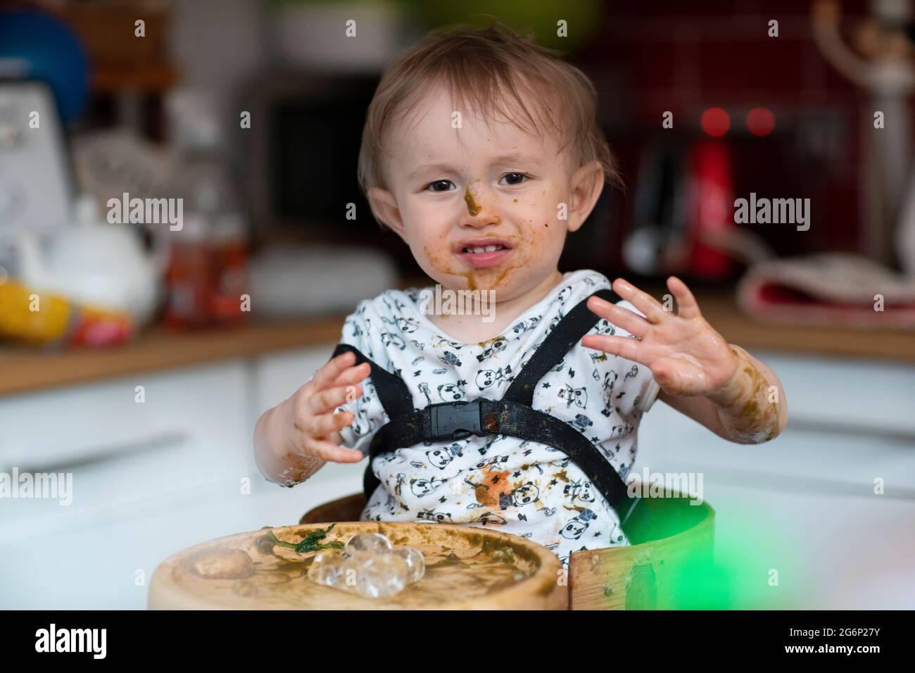 A baby eating messily in a high chair Stock Photo - Alamy
