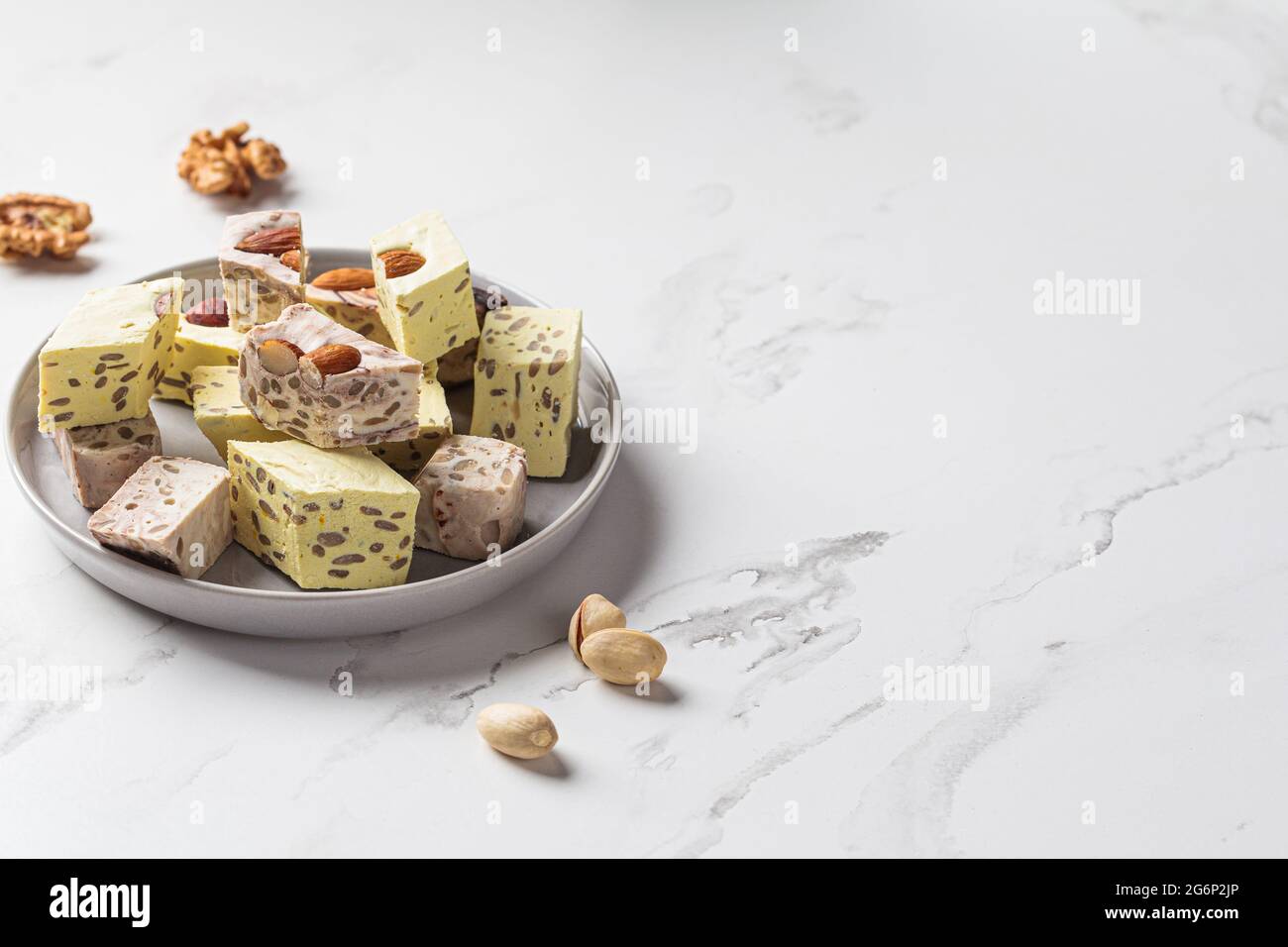 Pieces of different types of halva on a gray plate, white marble ...