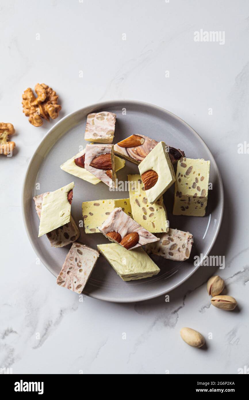 Pieces of different types of halva on a gray plate, white marble ...