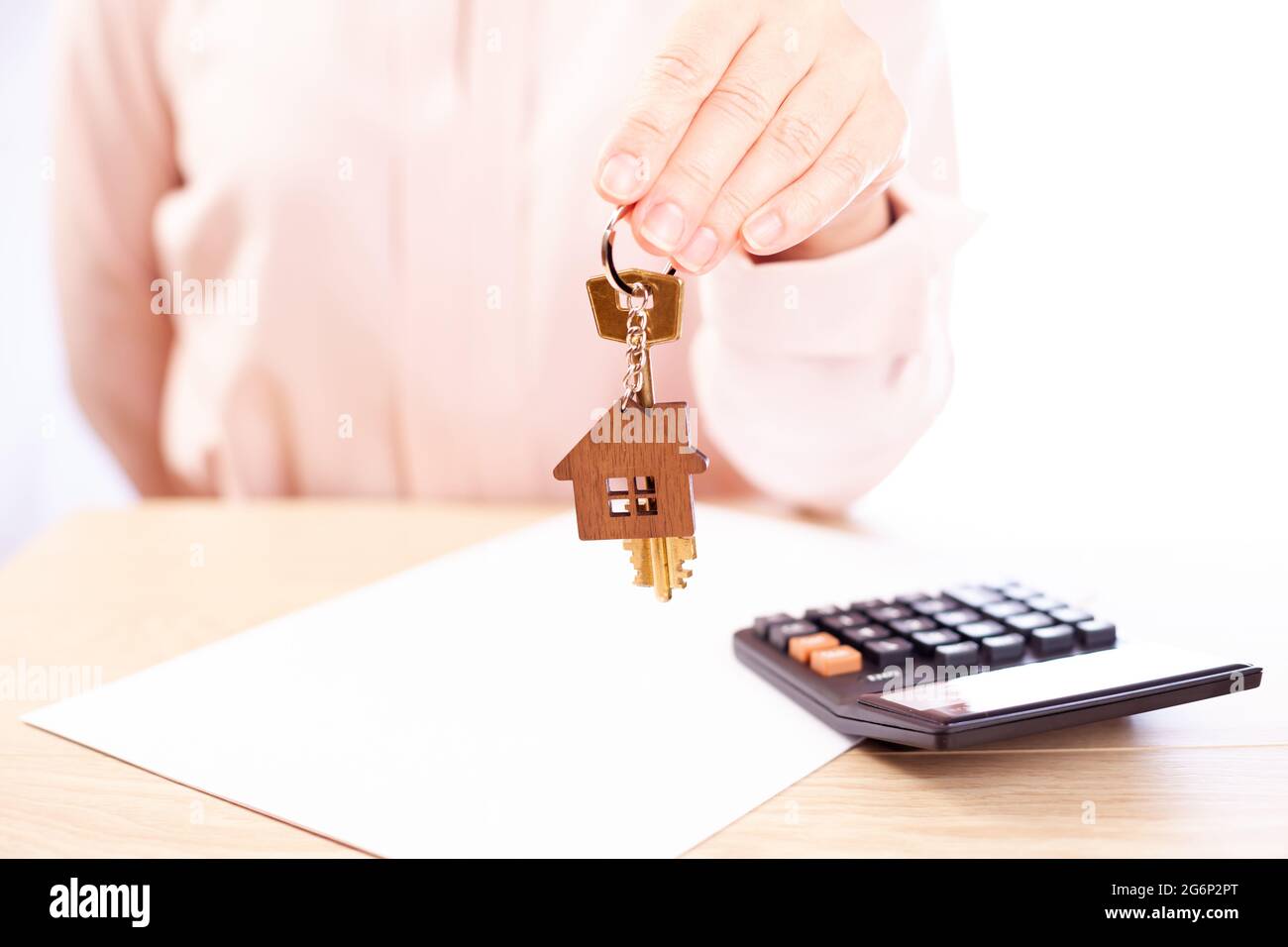 Realtor holds key to house, rental agreement Stock Photo - Alamy