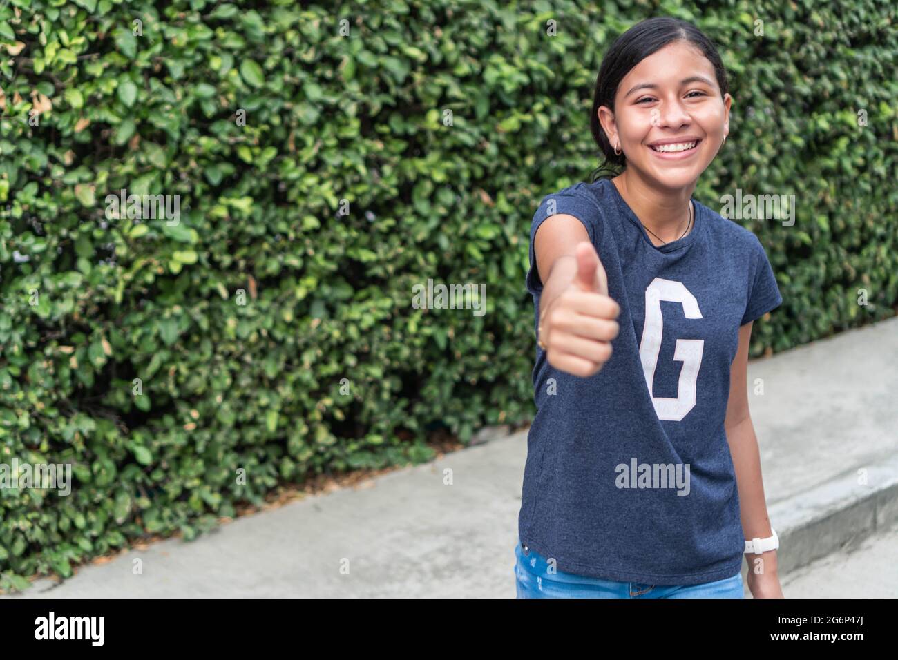 Hispanic teenager making positive hand gesture, thumbs up smiling and ...