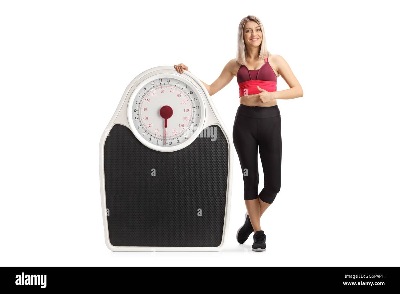 Full length portrait of a sporty woman leaning on a big weight scale ...