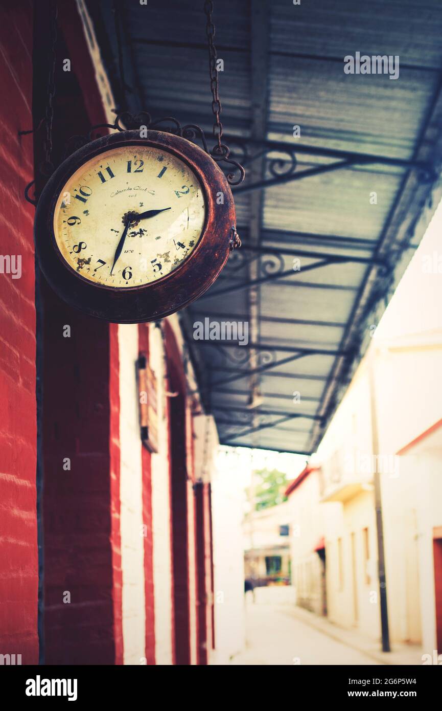 Old fashioned clock hanging outside a closed corner shop in a Greek ...