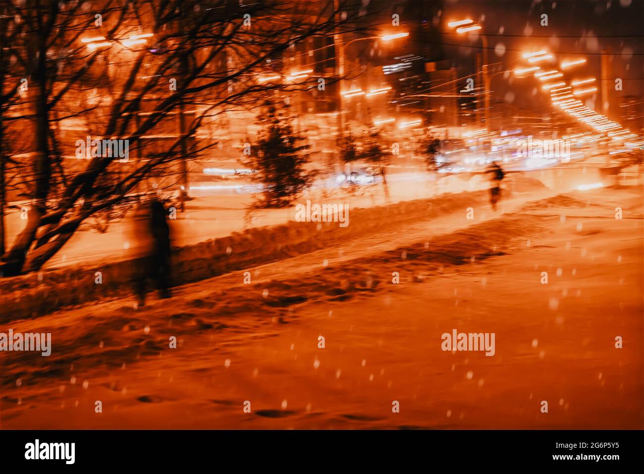 Abstract blurred background of night illuminated city street, snow and ...